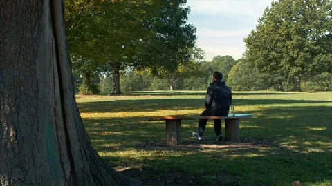A STATIC WIDE SHOT of a young man sittin... | Stock Video | Pond5