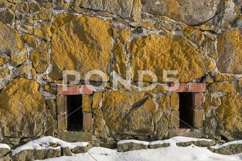 Stone wall texture and windows with red frames, natural background ...