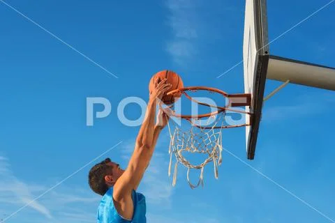 Photograph: Street basketball athlete performing slam dunk on the court ...