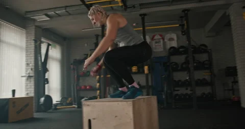 Strong female athlete jumping on cube | Stock Video | Pond5