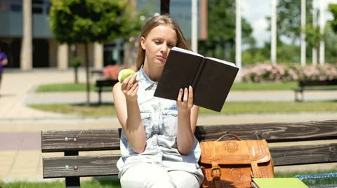 Student eating an apple and reading a bo... | Stock Video | Pond5