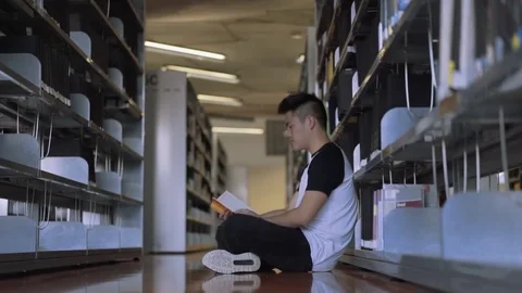 Student sitting on the floor in library ... | Stock Video | Pond5