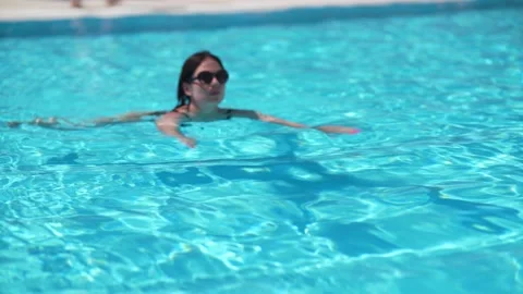 Stylish brunette girl swimming in blue s... | Stock Video | Pond5