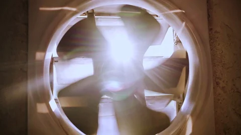 Sun rays through spinning fan in wall | Stock Video | Pond5