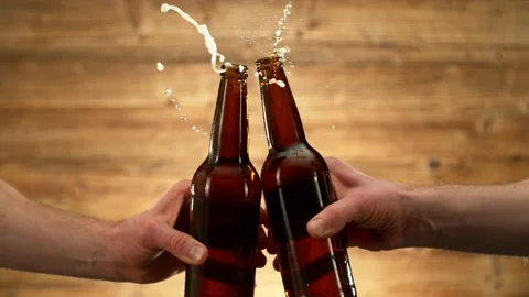 Super slow motion of hitting beer bottles together cheers concept