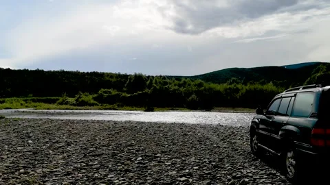 SUV on the bank of a mountain river Alre... | Stock Video | Pond5