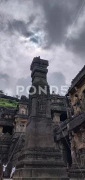 A tall stone pillar in front of a building at Kailasa Temple, Ellora ...