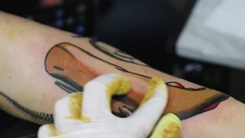 Tattoo artist detailing a fresh tattoo o... | Stock Video | Pond5