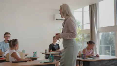 The teacher walks around the classroom o... | Stock Video | Pond5