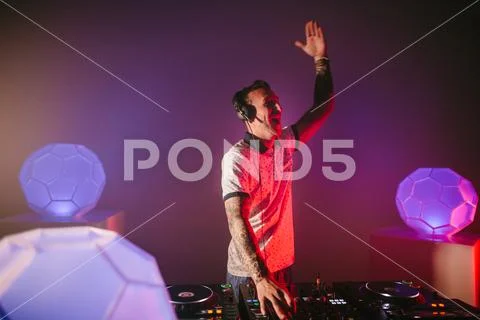 Photograph: Techno DJ screaming to the crowd in a red background #135388827