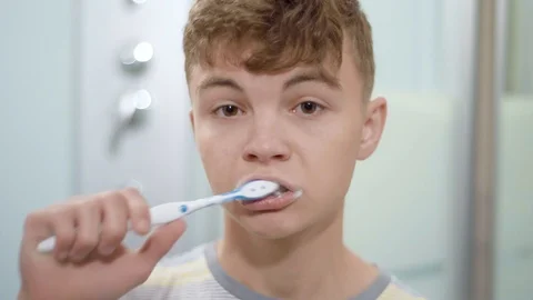 Teen boy brushing teeth | Stock Video | Pond5