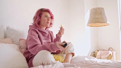 Teen girl with pink hair watching tv in ... | Stock Video | Pond5