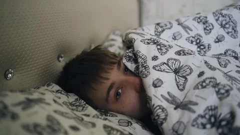 A teenage boy wakes up and looks out fro... | Stock Video | Pond5
