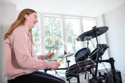Teenage Girl Having Fun Playing Electronic Drum Kit At Home ~ Hi Res #104423433