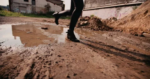 Teenage girl jumping over muddy puddle i... | Stock Video | Pond5