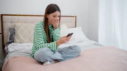 Teenage girl sits on bed, checks content... | Stock Video | Pond5