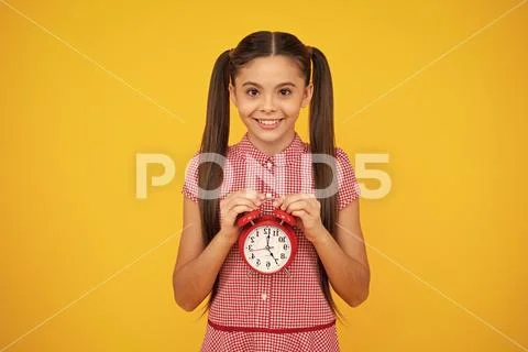 Photograph: Teenager child hold clock isolated on yellow studio ...