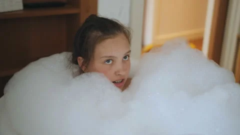 Teenager girl takes a bath full of foam. | Stock Video | Pond5