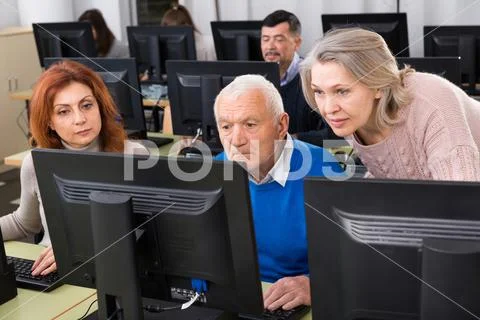 Three coworkers working around computer monitor, talking about new ...