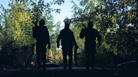 Three dark shapes of armed men walk in t... | Stock Video | Pond5