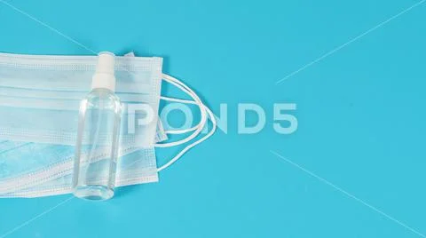 Photograph: Three face masks and alcohol spray on blue background ...