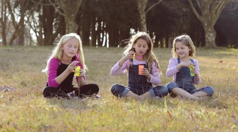 Three girls kids sisters blowing bubbles... | Stock Video | Pond5
