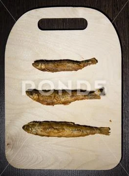 Three little fried fish on a wooden cutting board. ~ Premium Photo ...
