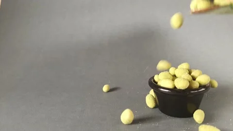Throwing wasabi peanuts in a black bowl ... | Stock Video | Pond5