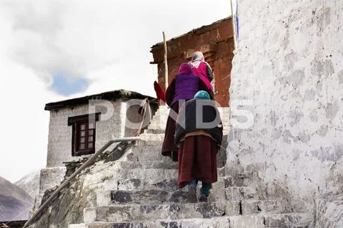 Tibetan pilgrim people walk on stone stairs step up approach to Diskit ...