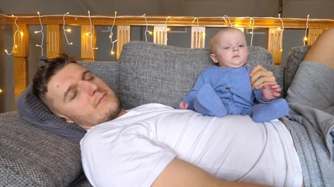 Tired Father Sleeping With Cheerful Baby | Stock Video | Pond5