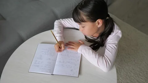 Top view schoolkid sit at desk write in ... | Stock Video | Pond5