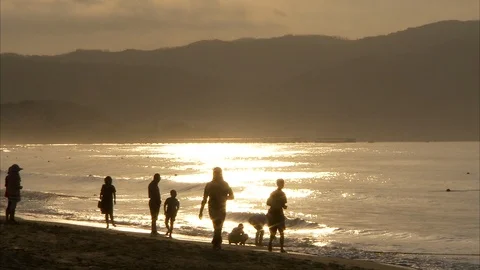 Tourists relaxing on the beach at sunset | Stock Video | Pond5