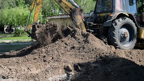 Tractor pits the ground. Backhoe piles u... | Stock Video | Pond5