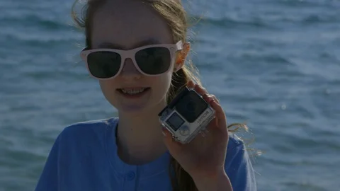 tween girl with camera at ocean smiles | Stock Video | Pond5