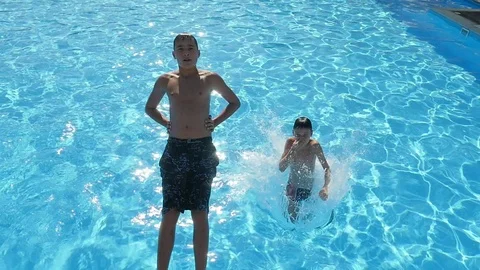 Two boys are falling in a swimming pool ... | Stock Video | Pond5