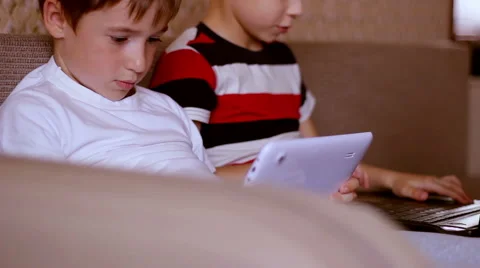 Two boys playing on a tablet and a lapt... | Stock Video | Pond5