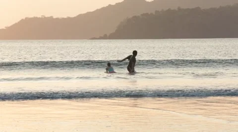 Two children playing in the waves on the... | Stock Video | Pond5