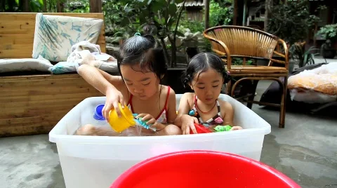 Two Chinese girls bathing in the backyar... | Stock Video | Pond5