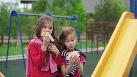 Two girls eating sandwiches outdoor on c... | Stock Video | Pond5