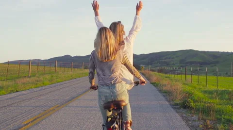 Two Girls Riding Bike At Sunset With Han... | Stock Video | Pond5