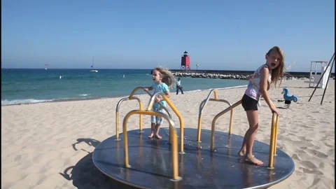 two girls spinning on roundabout in sand... | Stock Video | Pond5