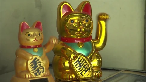 Two golden cat statues waving arms | Stock Video | Pond5