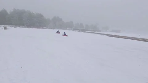 Two kids racing with sleds and one of th... | Stock Video | Pond5
