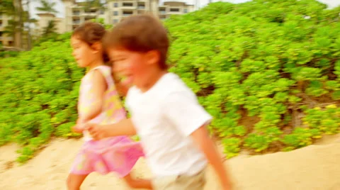Two kids run down the beach and into the... | Stock Video | Pond5