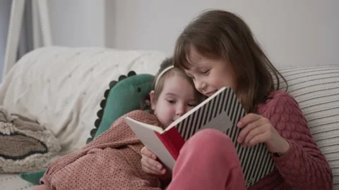 Two Little Girls Read a Book Together an... | Stock Video | Pond5