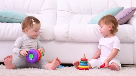 Two little kids sit on carpet and play w... | Stock Video | Pond5