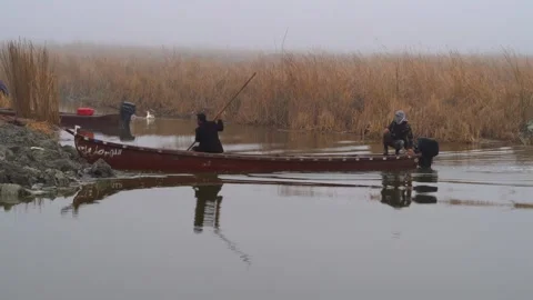 Two men arrive at shore in mashoof canoe... | Stock Video | Pond5