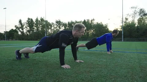 Two men doing push-ups on a soccer field... | Stock Video | Pond5