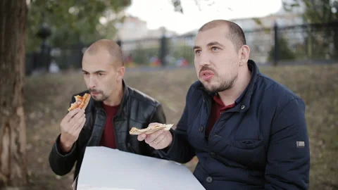 Two men on a Park bench eating a takeawa... | Stock Video | Pond5