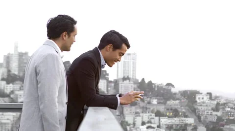 Two men stand on a roof while wearing su... | Stock Video | Pond5